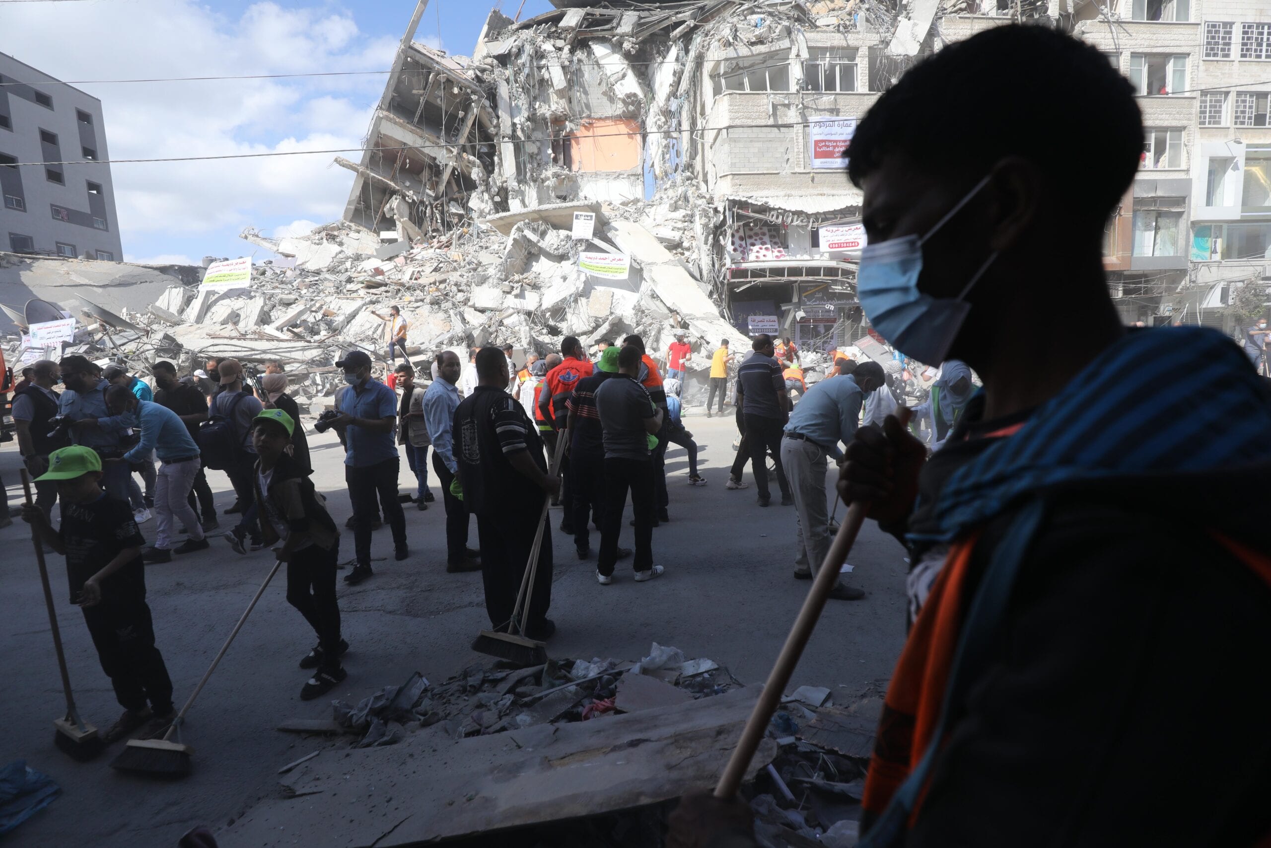 Palestinian volunteers sweep the rubble of buildings destroyed by ...