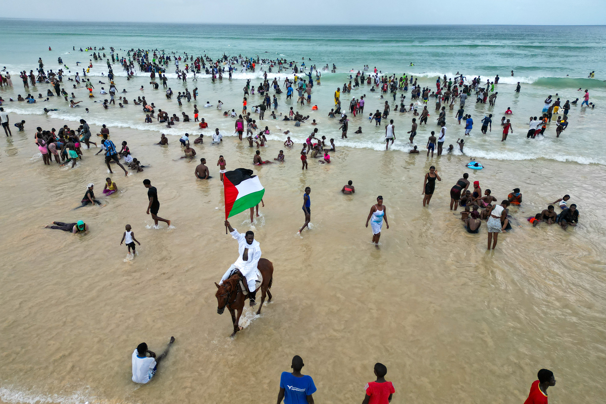 Performance artist in Senegal rides horse along Dakar beach in ...